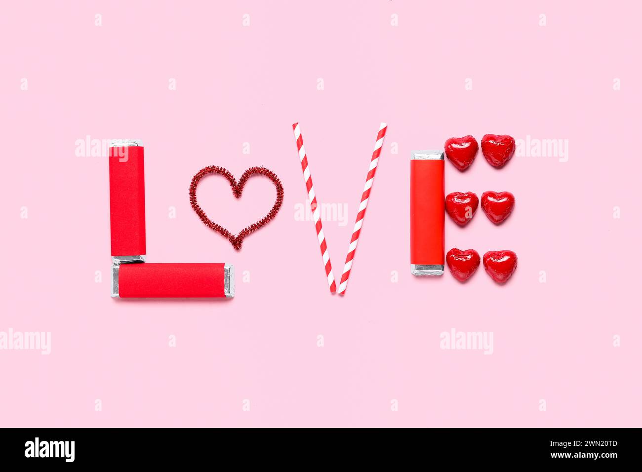 Word LOVE made of chocolate, candies and straws on pink background ...