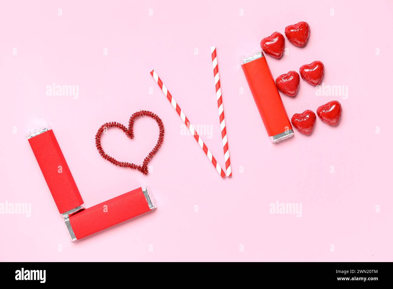 Word LOVE made of chocolate, candies and straws on pink background ...
