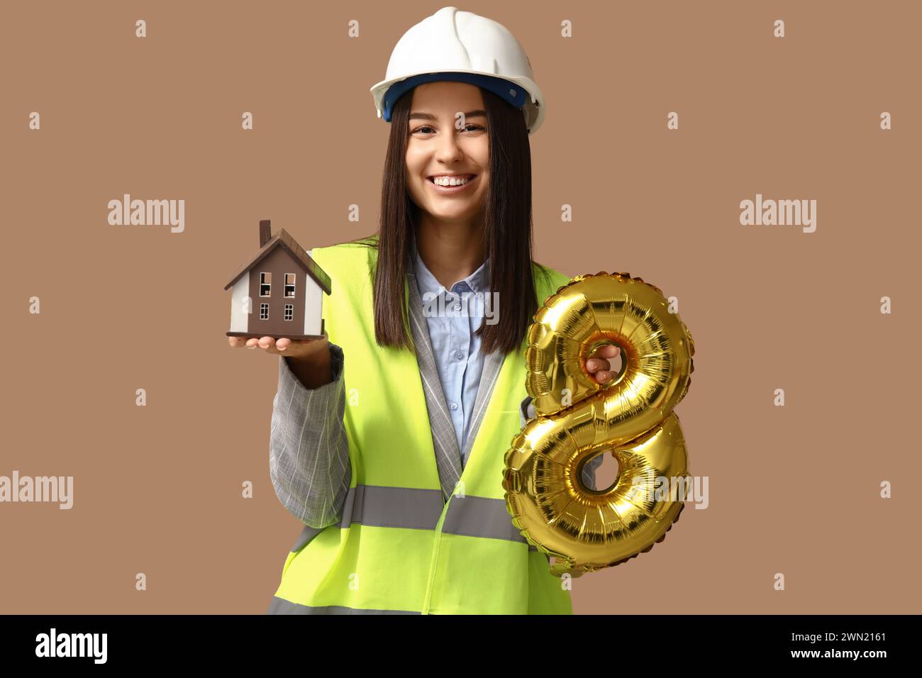 Female construction worker with toy house and balloon in shape of ...