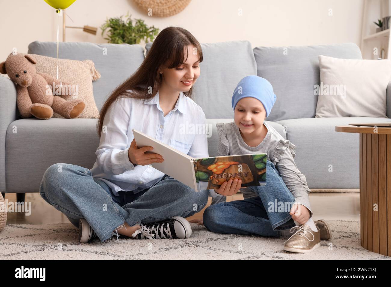 Little girl after chemotherapy with her mother reading story at home ...