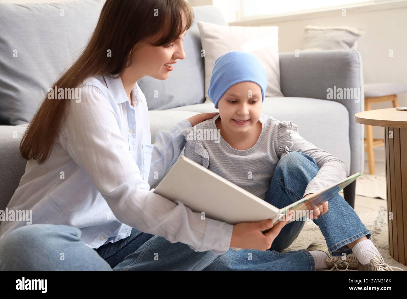Little girl after chemotherapy with her mother reading story at home ...