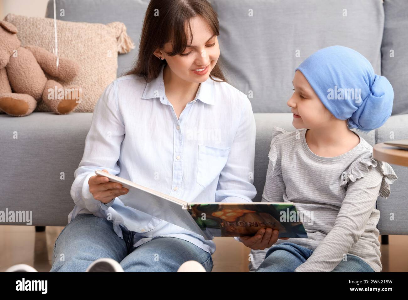 Little girl after chemotherapy with her mother reading story at home ...