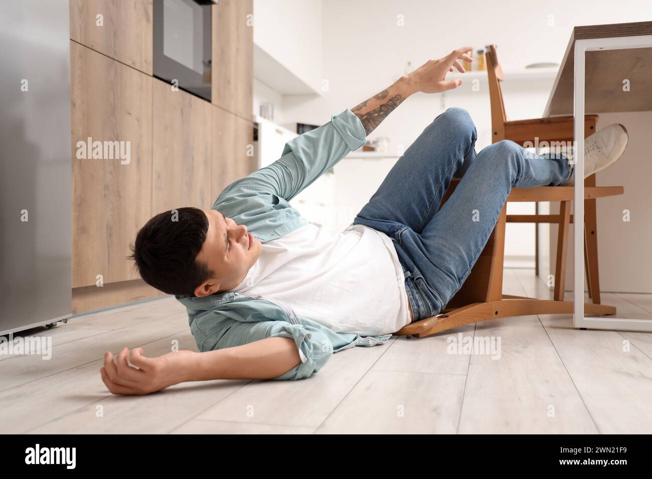 Young man fell down from chair in kitchen. Trauma concept Stock Photo ...