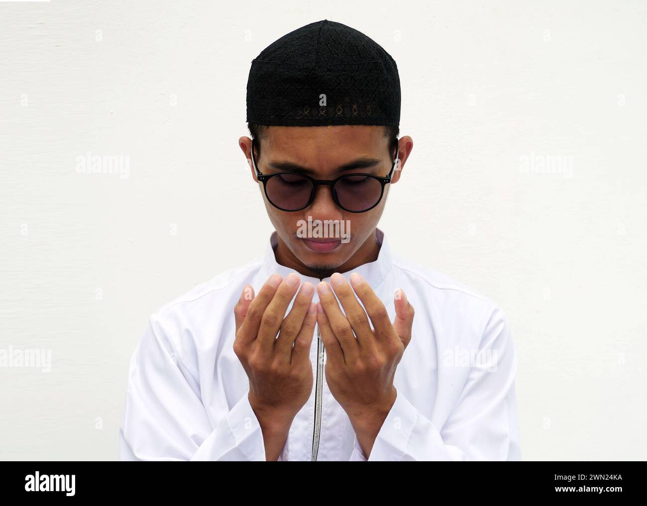 Young Muslim man in Malay Muslim clothing and glasses is praying ...