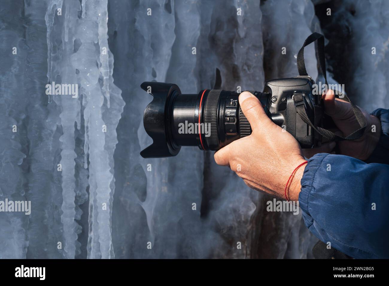 photographer's hand with a DSLR camera takes pictures of icicles Stock ...