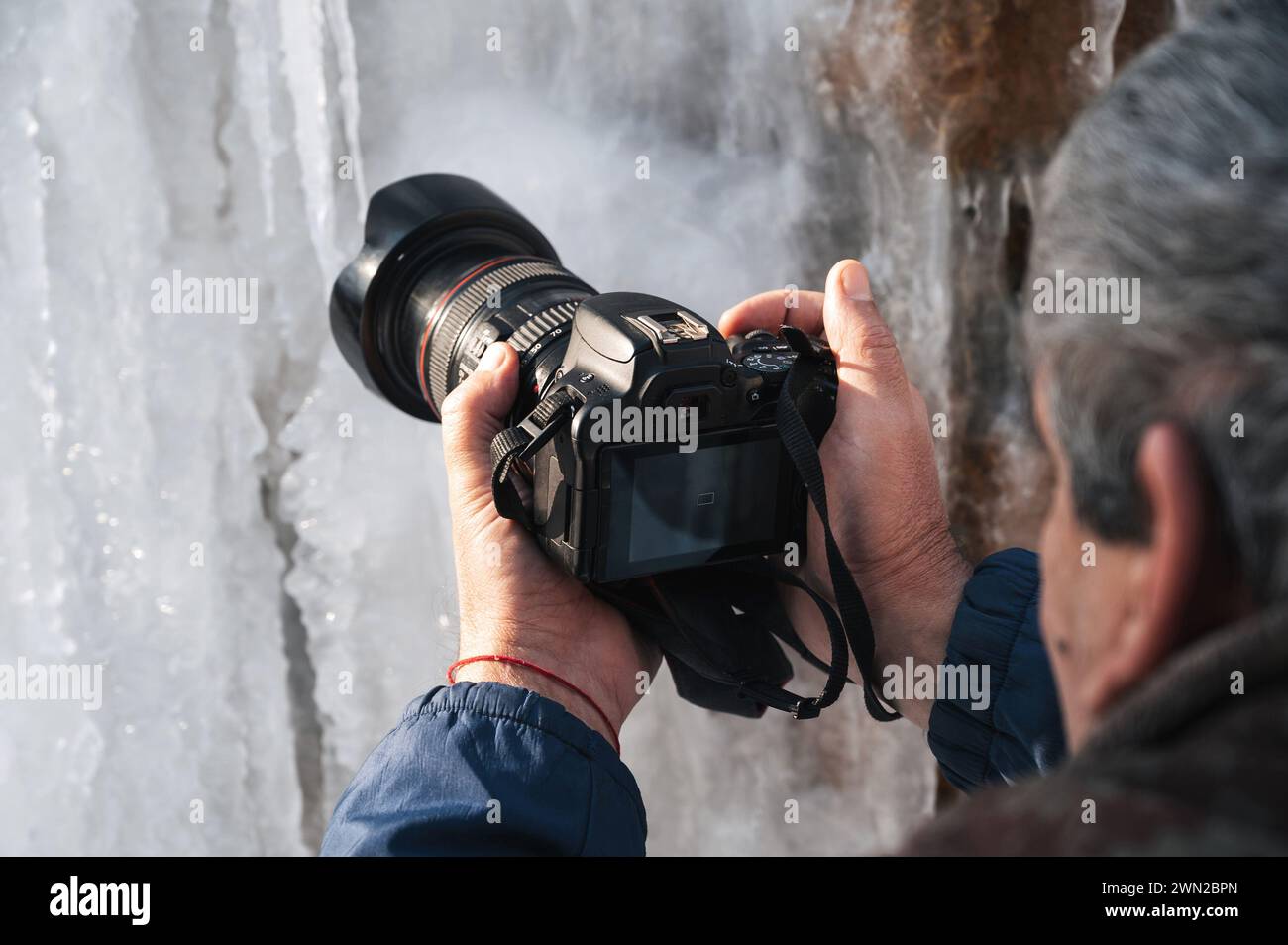 photographer's hand with a modern DSLR camera shoots icicles in winter ...