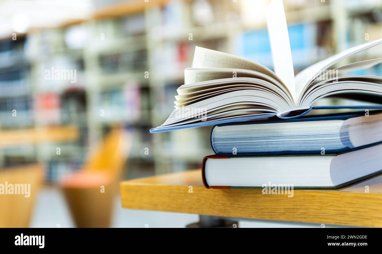 Stack of books opened on library desk Stock Photo - Alamy