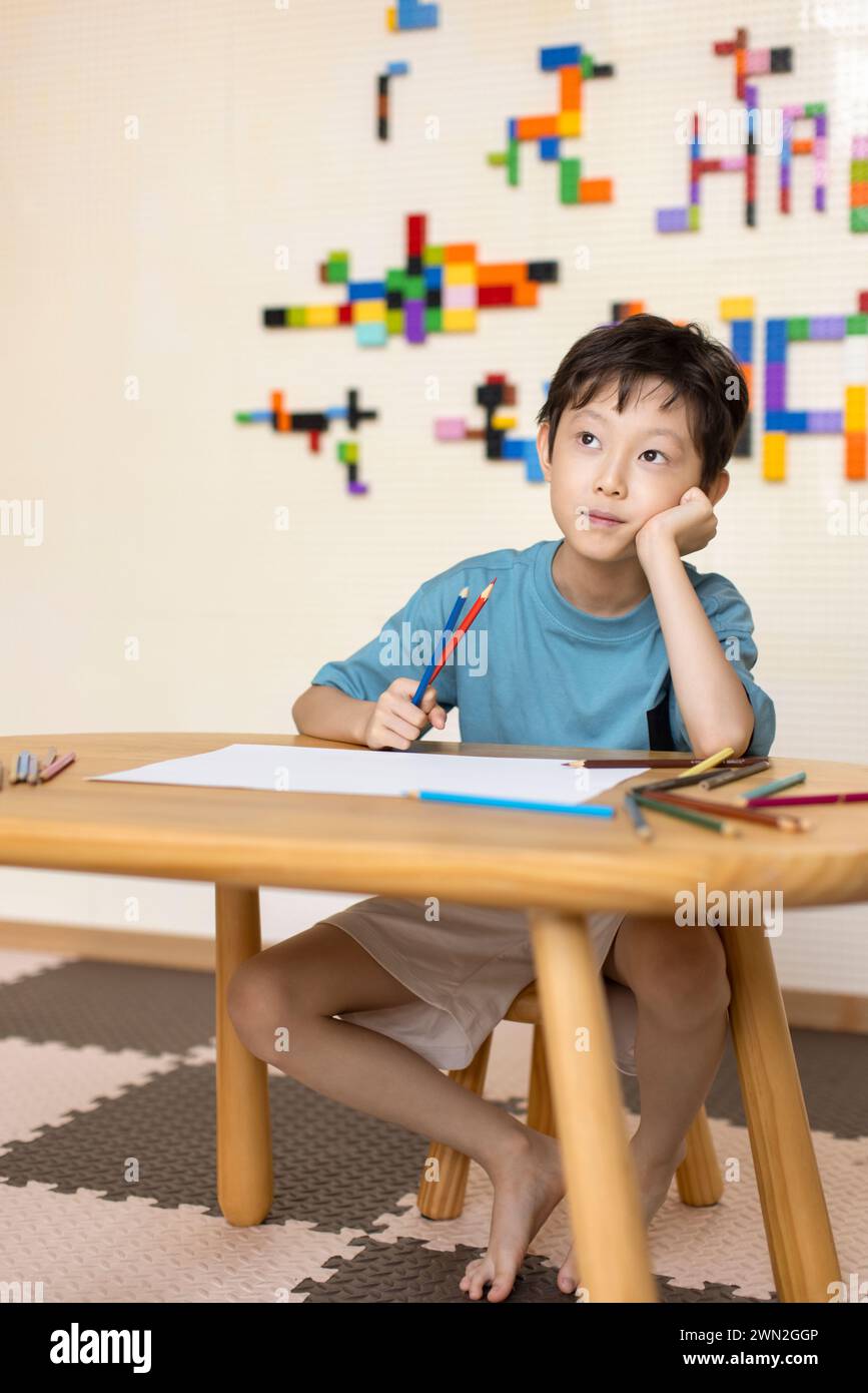 Cute boy thinking in classroom Stock Photo - Alamy