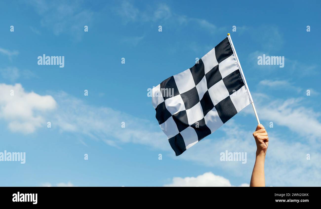 Checkered race flag in hand against blue sky Stock Photo - Alamy