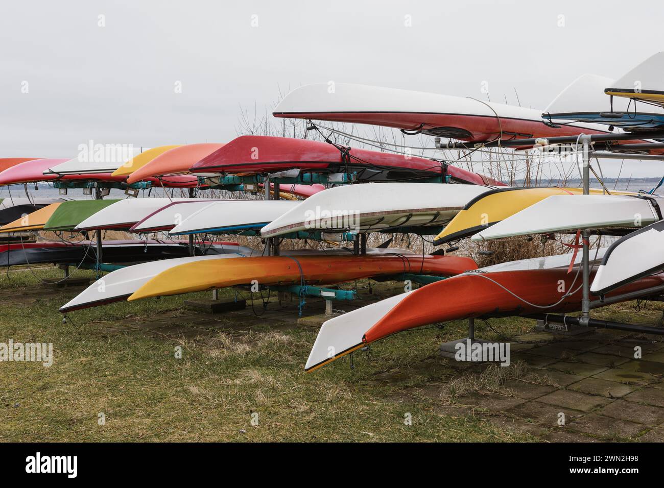 Many different colorful sea kayaks stored in a rack on land during ...