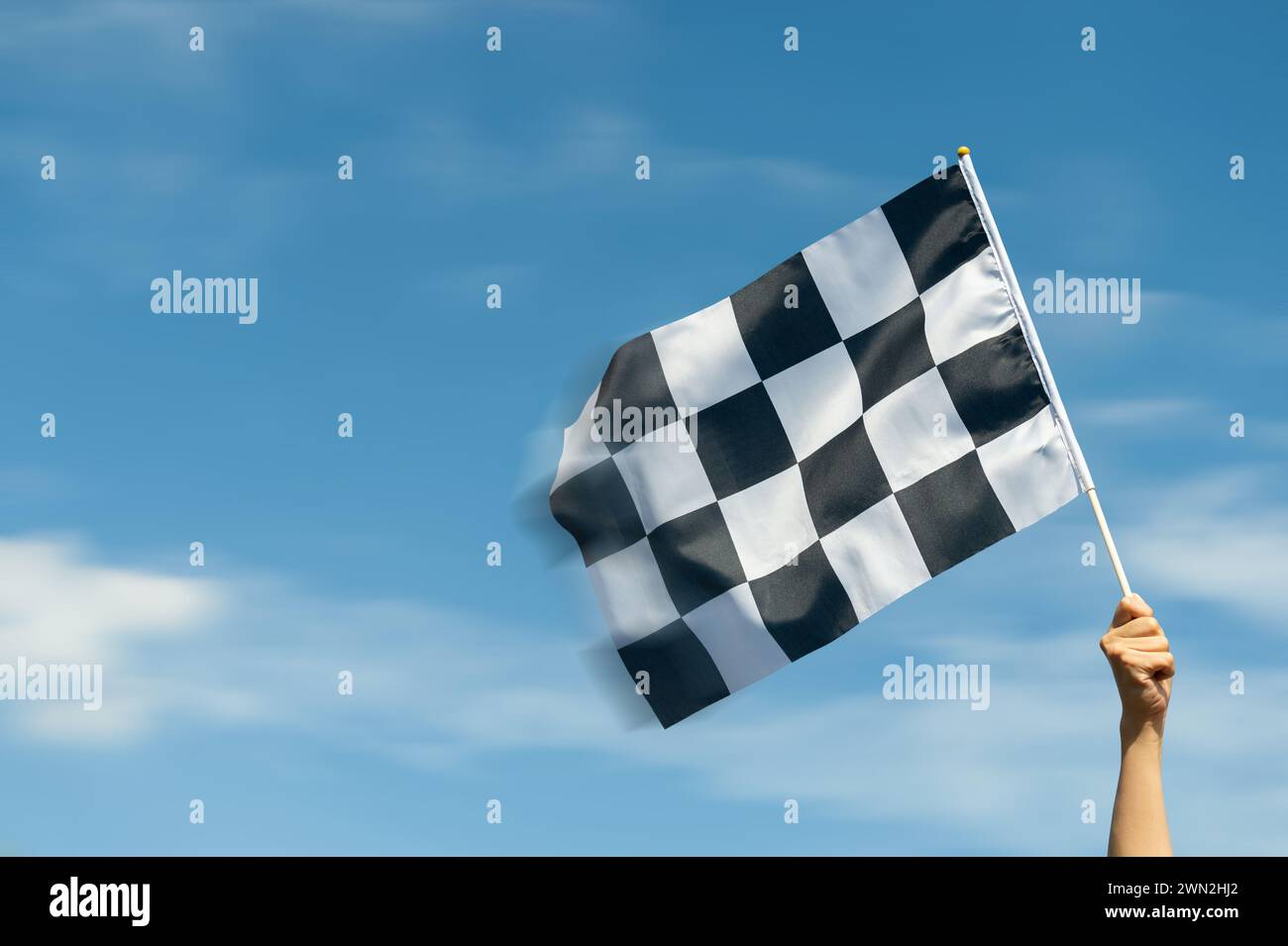 Checkered race flag in hand against blue sky Stock Photo - Alamy