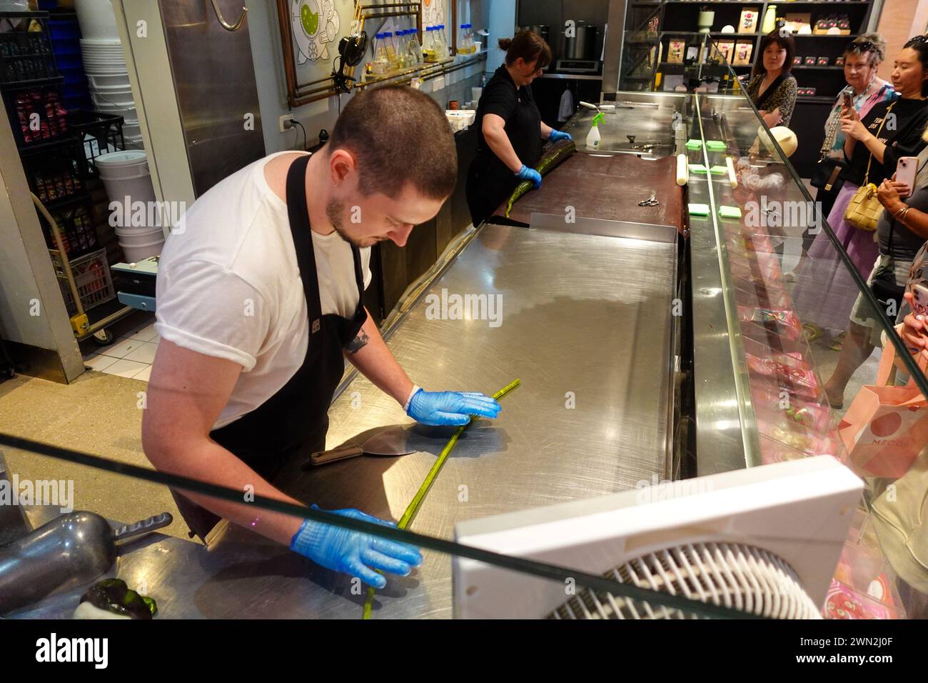 A young man is seen in the process of making candy, skillfully rolling ...