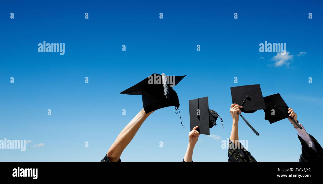 Four hands holding graduation hats against blue sky Stock Photo - Alamy