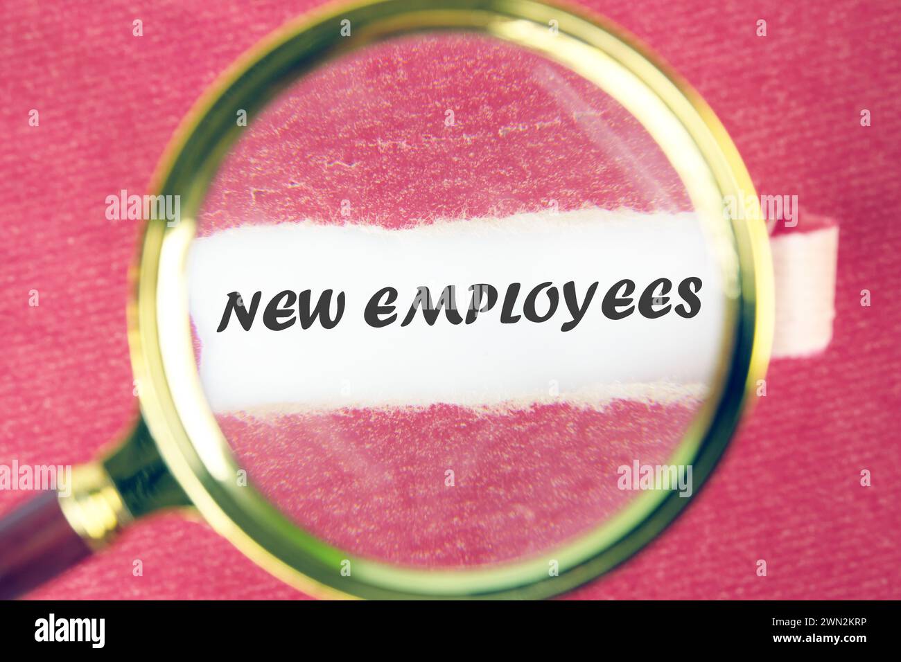 NEW EMPLOYEES Text through a magnifying glass under a torn piece of red ...