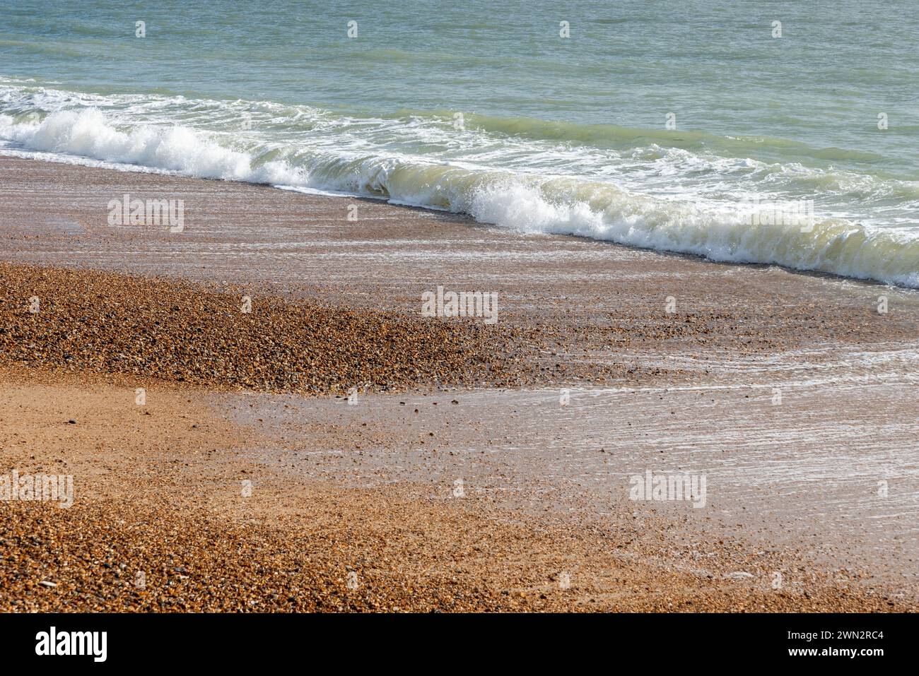 Clean and clear pebble beach with the sea breaking against the shore ...