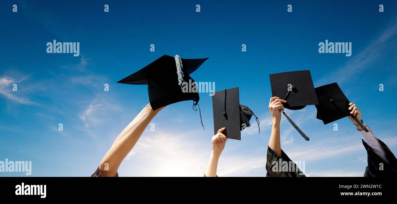 Four hands holding graduation hats against blue sky Stock Photo - Alamy
