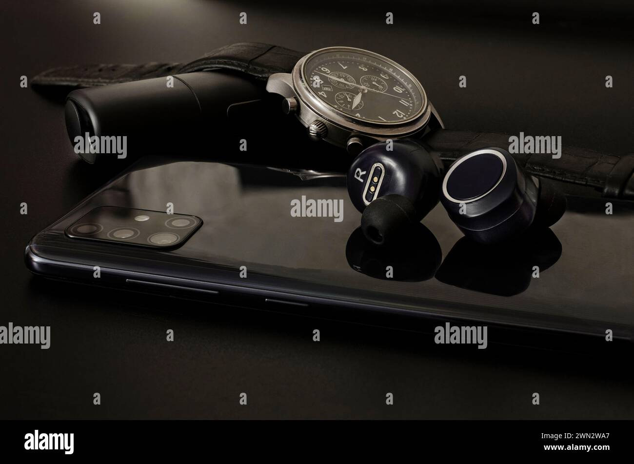 Gadgets on a dark background: a watch, headphones, a tobacco heater and ...