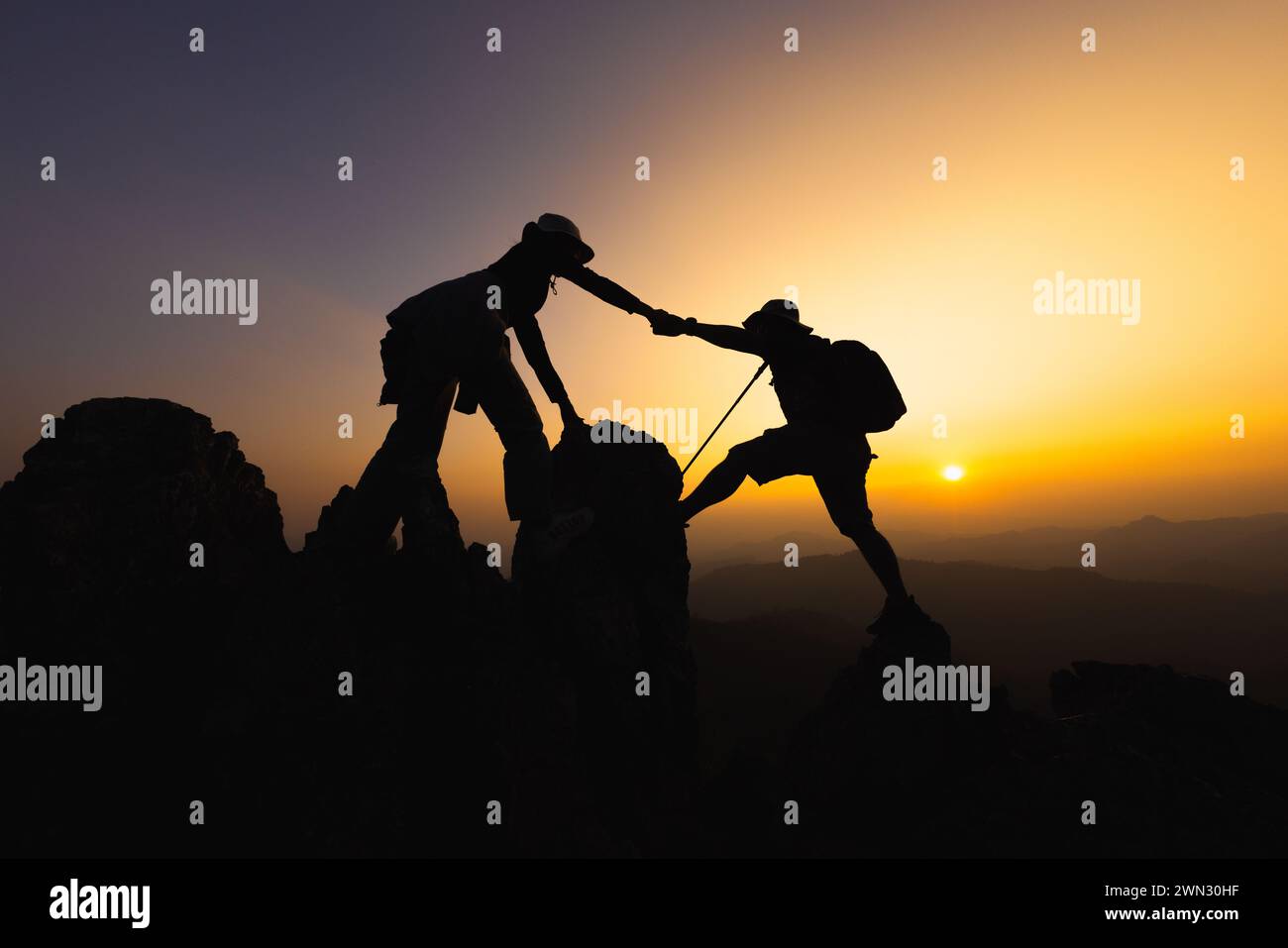 silhouette of People helping each other hike up a mountain at sunrise ...