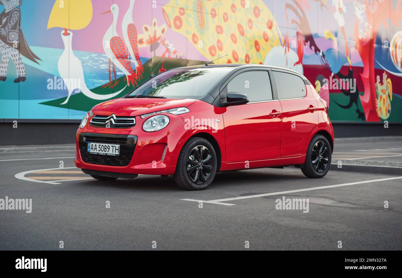red Citroen C1 in front of colorful wall. Front three quarter view of ...