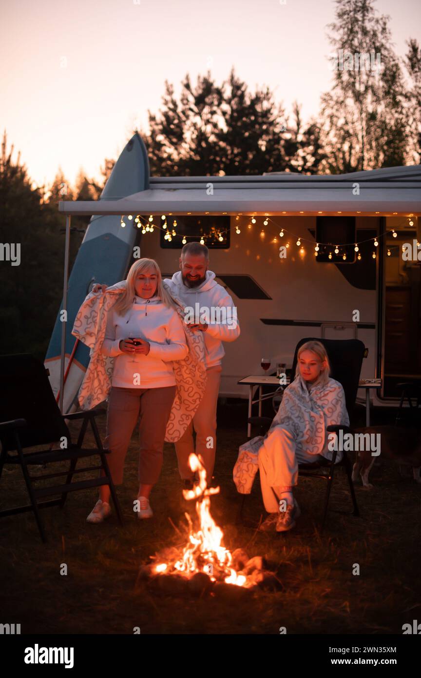 The family is relaxing together by the campfire near their mobile home ...