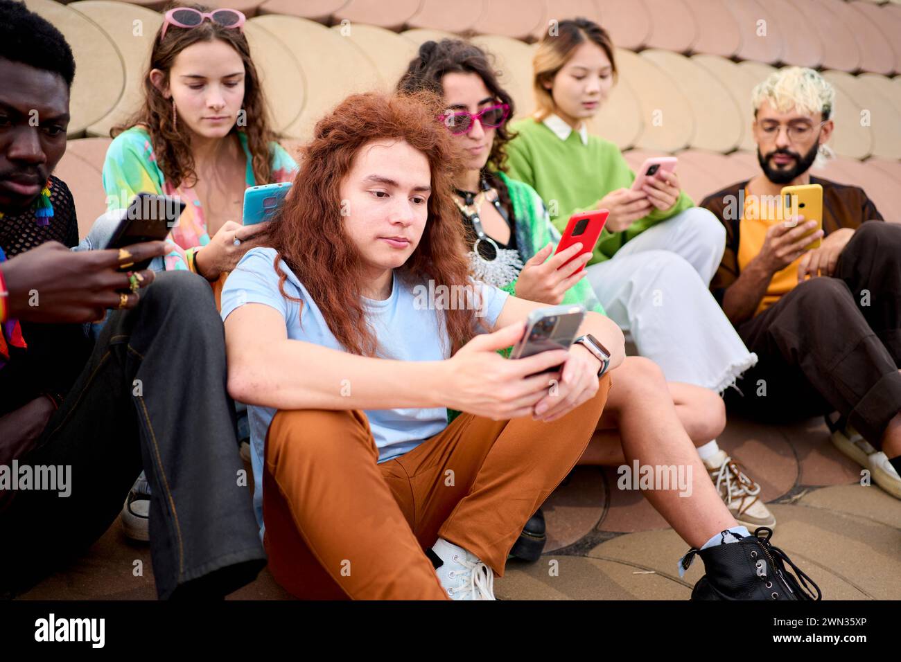 Side view large multiracial group young friends using cell phones ...