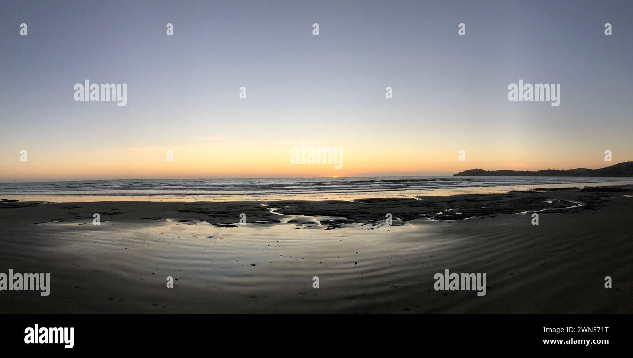 A sunset beach scene with sand and ocean waves Stock Photo - Alamy