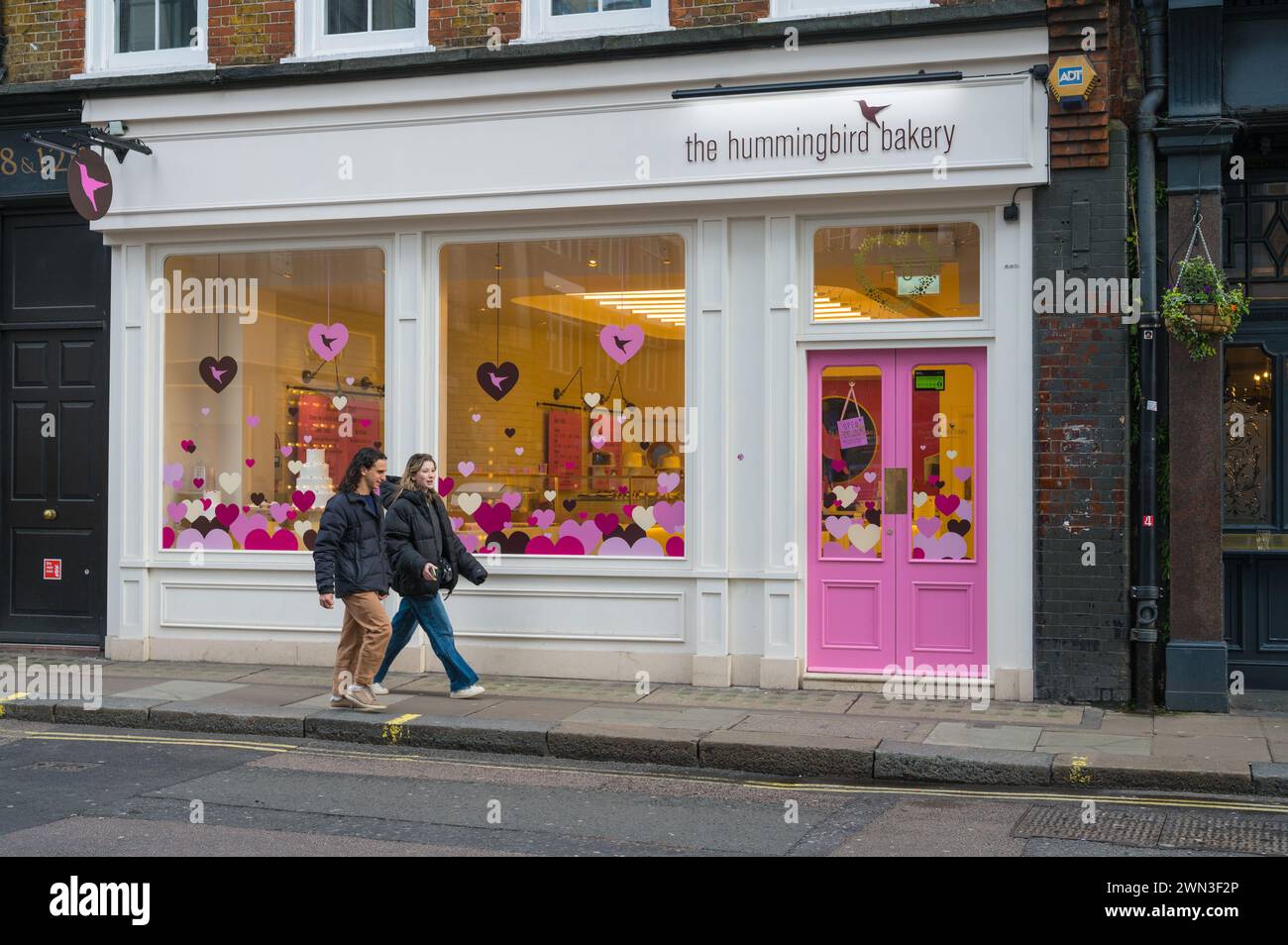Young woman and man walk past Hummingbird Bakery an American-style ...