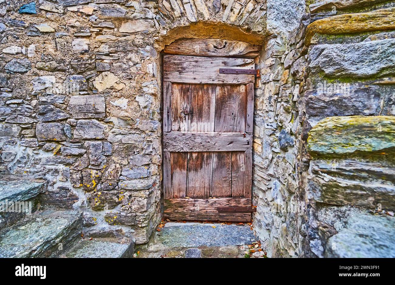 The wall of the medieval stone house and the vintage wooden door in ...