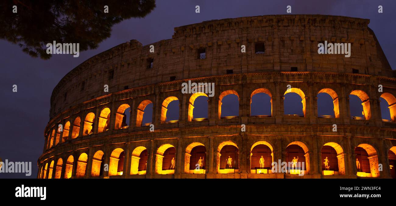 the wall of the colosseum with golden light at night in Rome, Italy ...