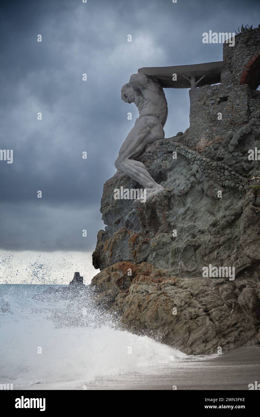 A giant statue on the rock with the waves crashed against the rock in ...