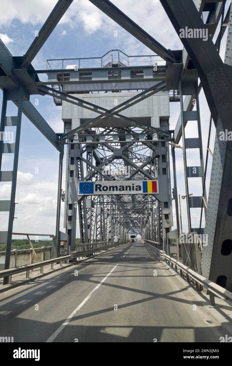 A steel bridge with a sign for Romania under a partly cloudy sky ...