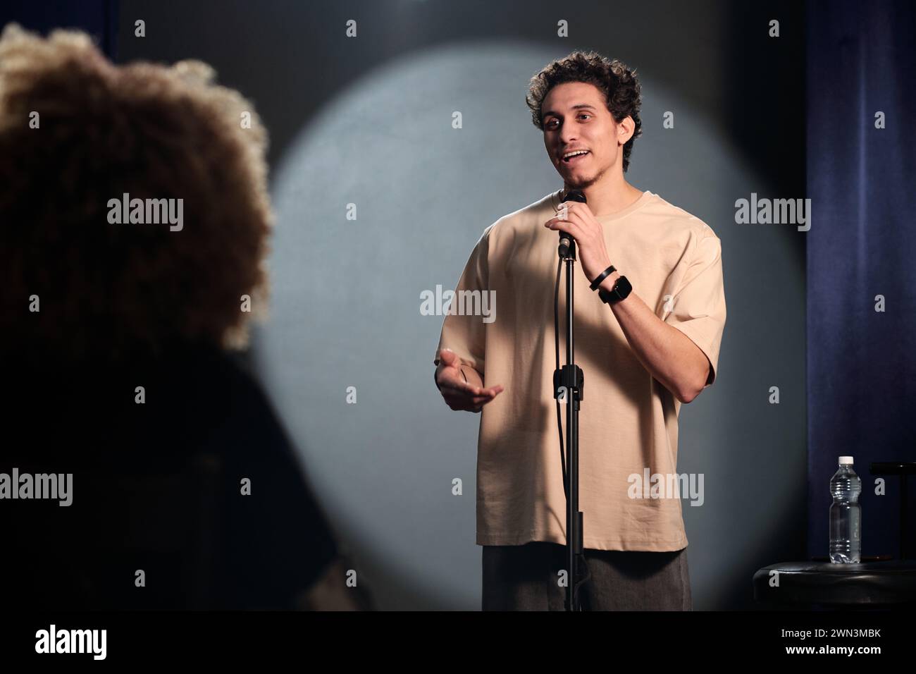 Young stand up comedian, actor or showman standing on stage in front of ...