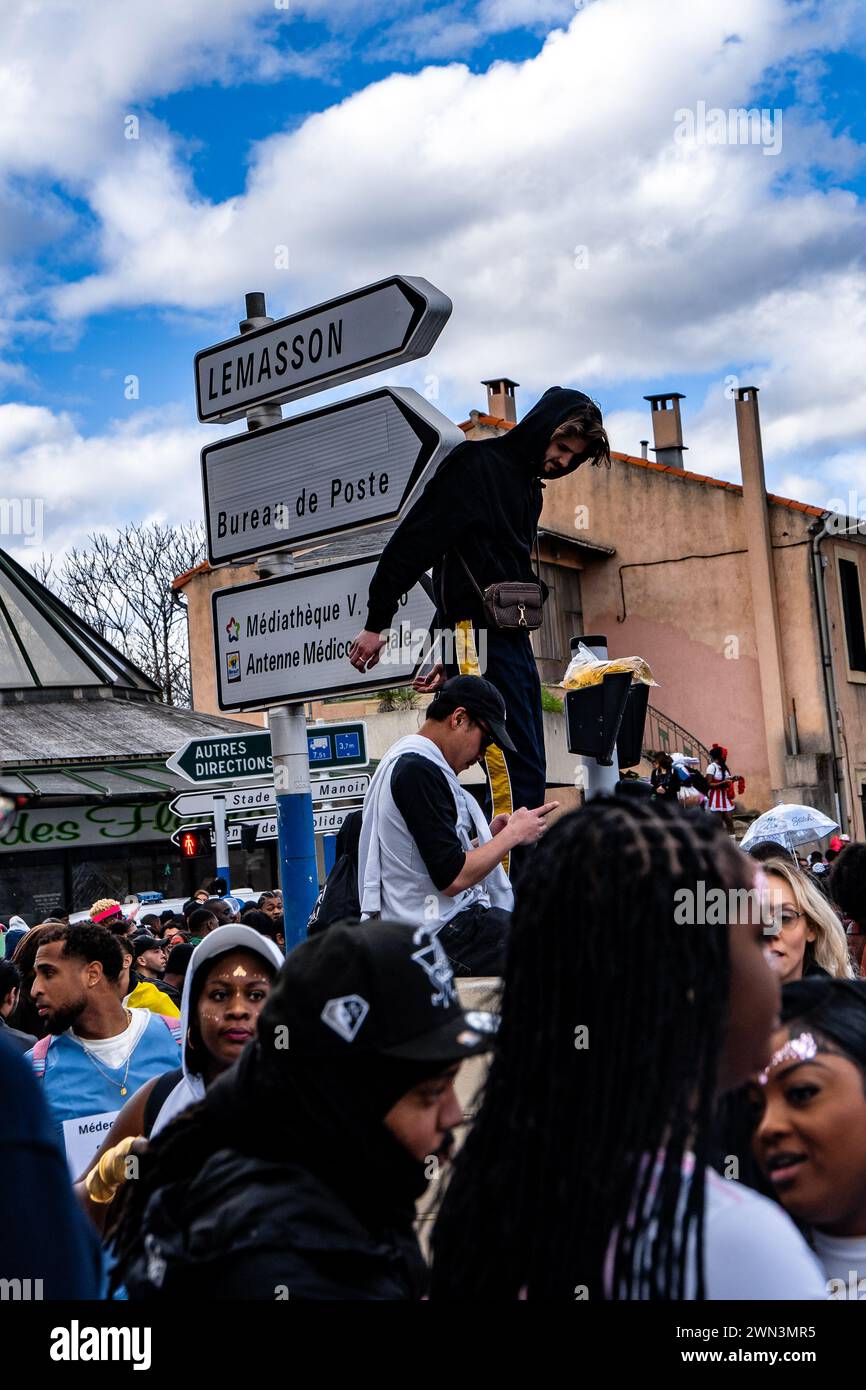 Crowd at urban intersection below street signs, in front of building ...