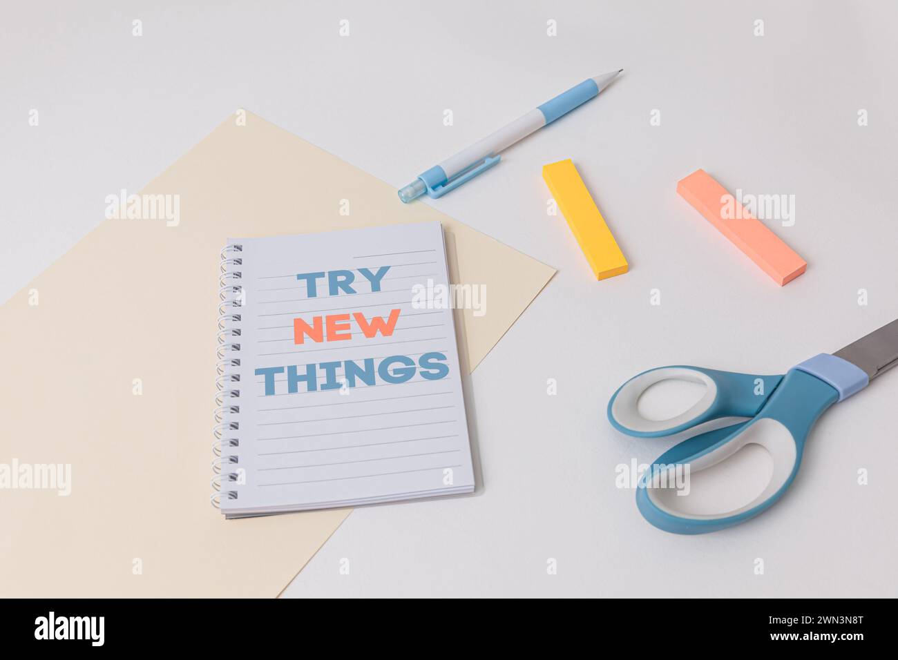 Notebook with Try new thing text is on top of white office desk table ...