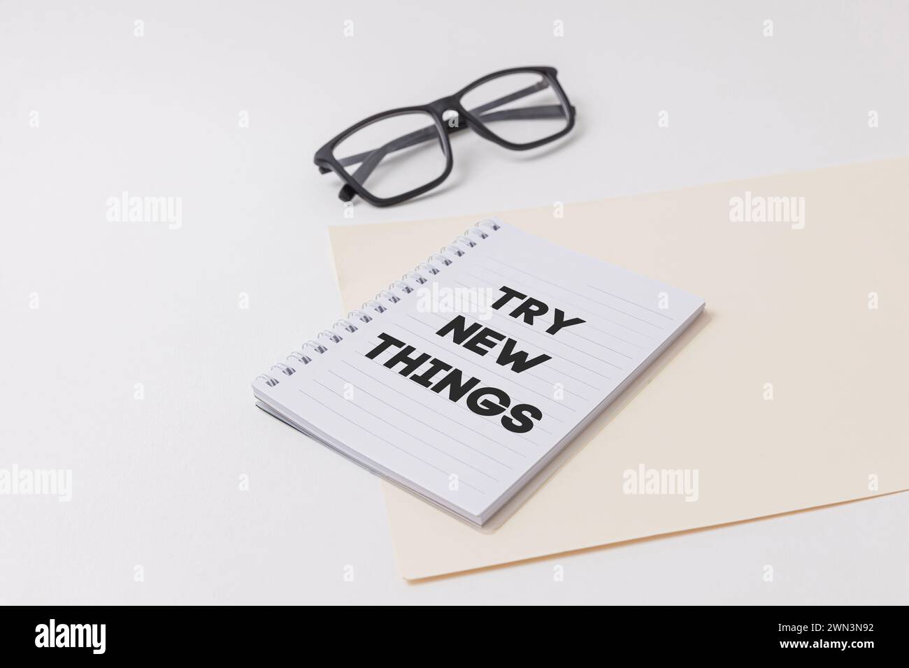 Notebook with Try new thing text is on top of white office desk table ...