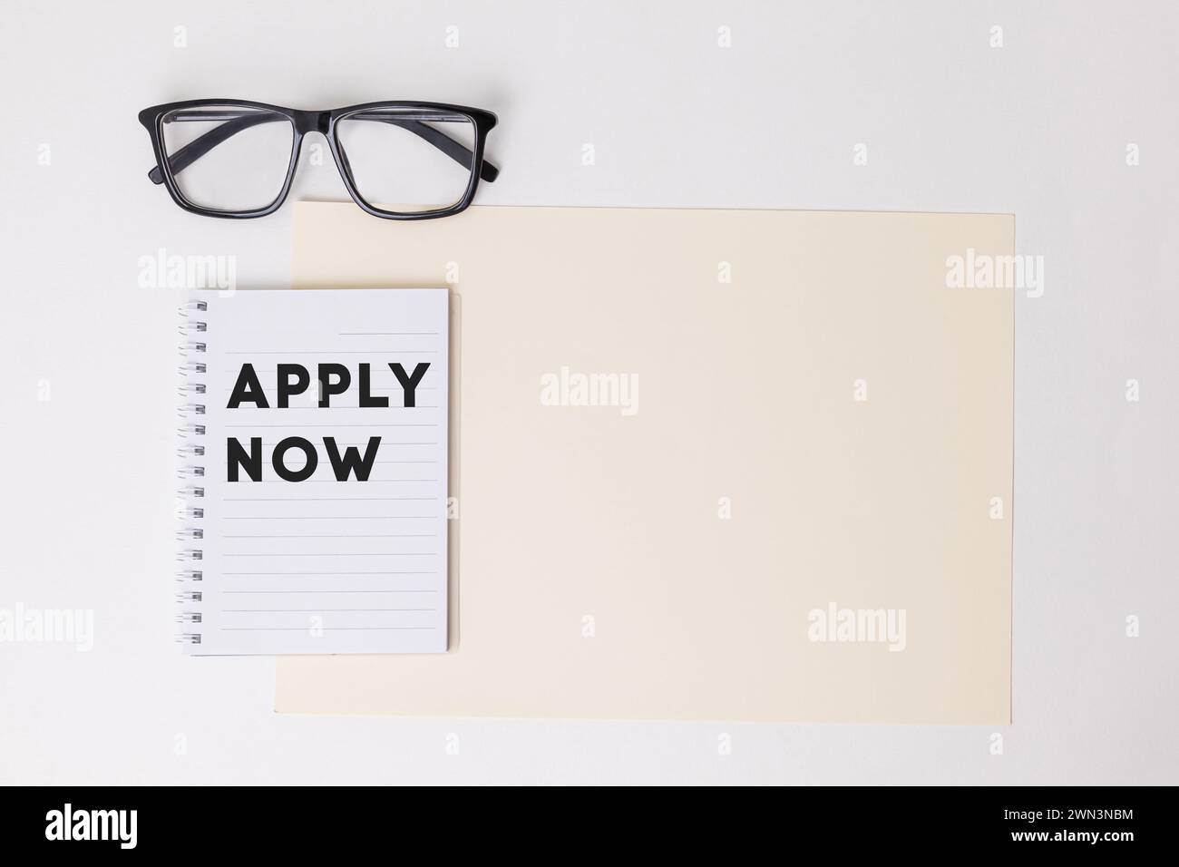 Notebook with Apply now text is on top of white office desk table with ...