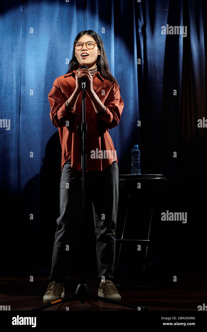 Young Asian female comedian of stand up club standing on stage with ...
