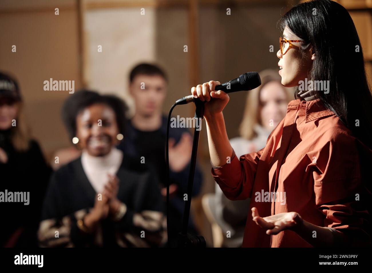 Young comedian of stand up show standing against audience and ...