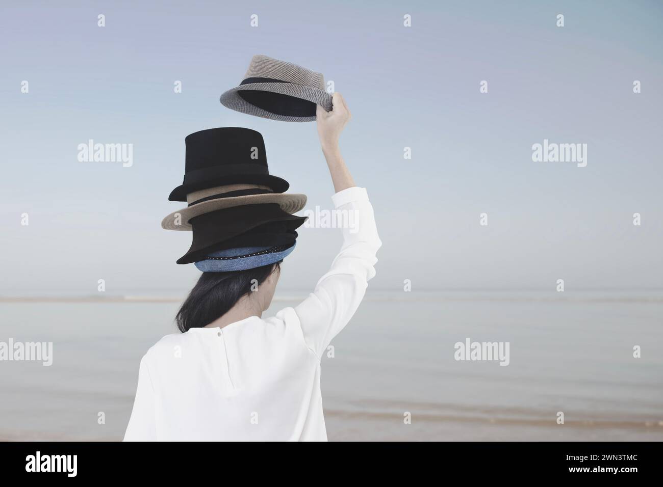 surreal woman from behind adds another hat on her head to the tower of ...