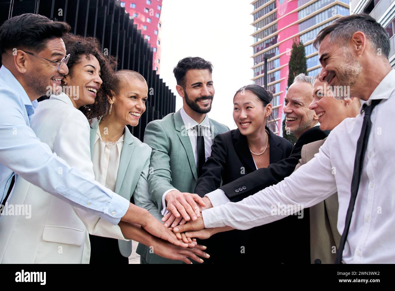 Diverse excited business team in suits joining hands in community ...