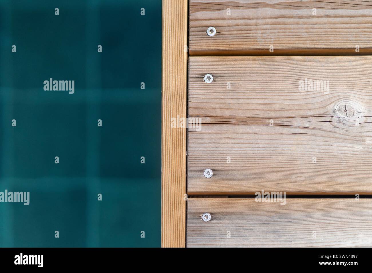 Poolside wooden deck and dark blue water background Stock Photo - Alamy