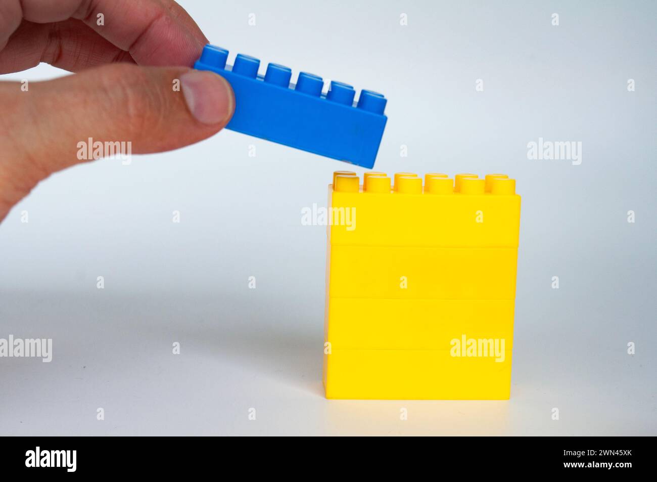 Hand stacking blue color lego on other lego set. Building concept Stock ...