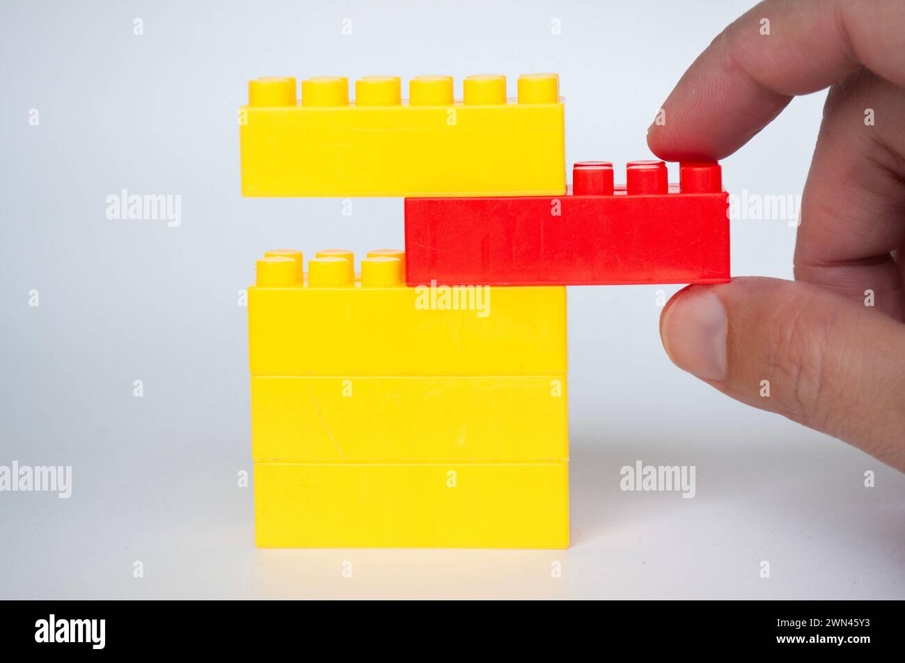 Hand pulling red lego from the rest. Building concept Stock Photo - Alamy