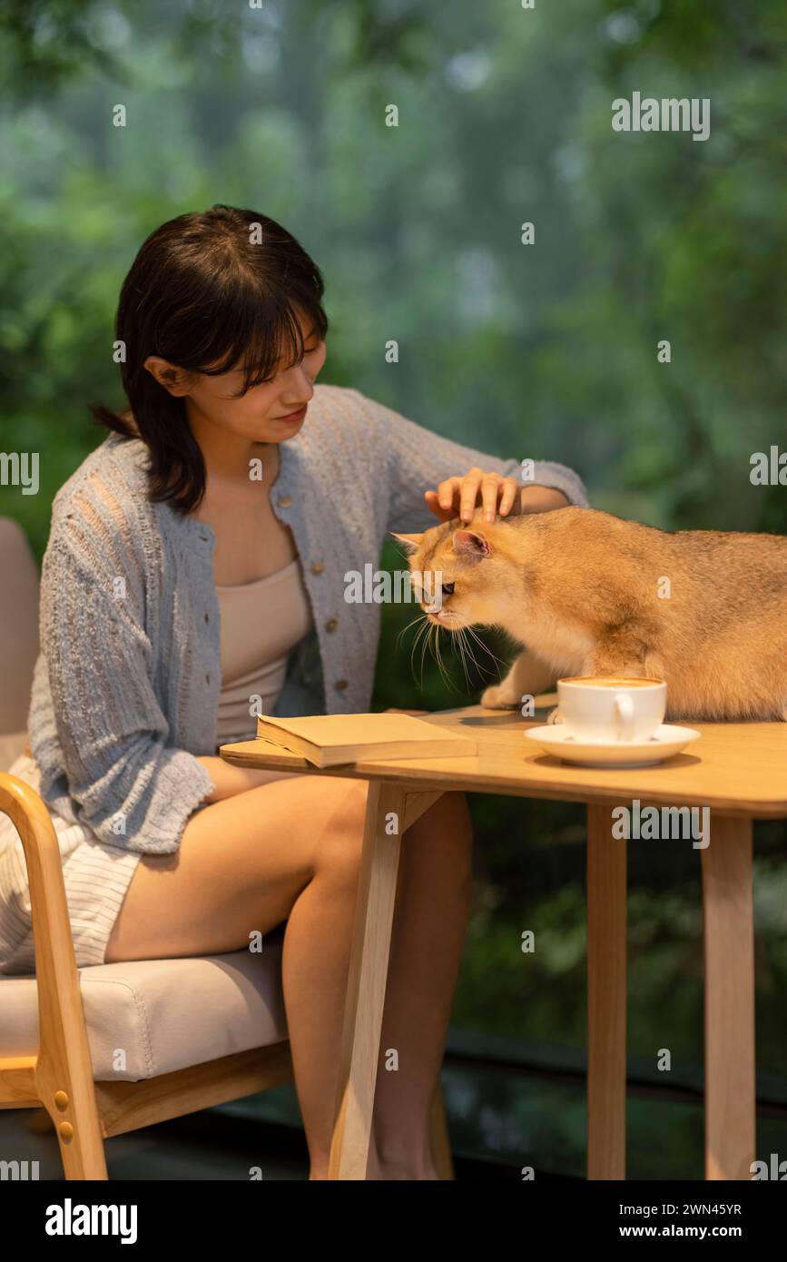 Young woman enjoying coffee in cat café Stock Photo - Alamy