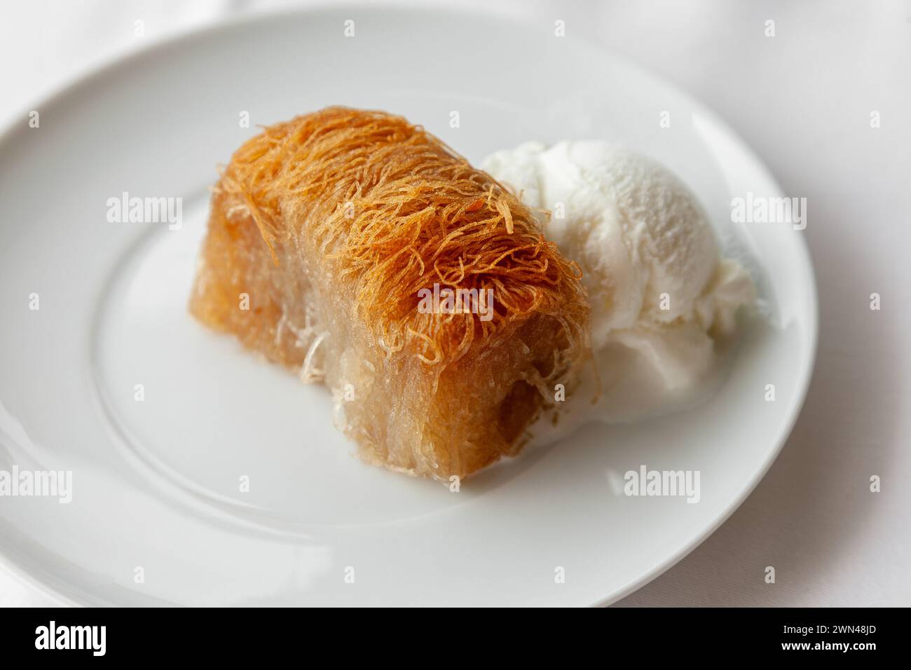 Traditional greek dessert kataifi served with ice cream on a white ...