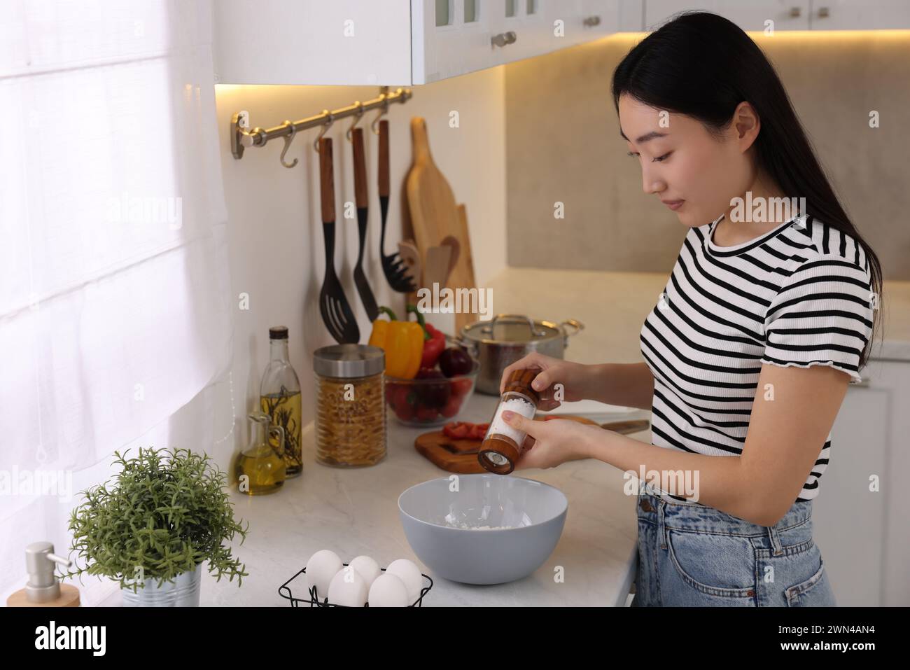 Cooking process. Beautiful woman adding salt into bowl in kitchen Stock ...