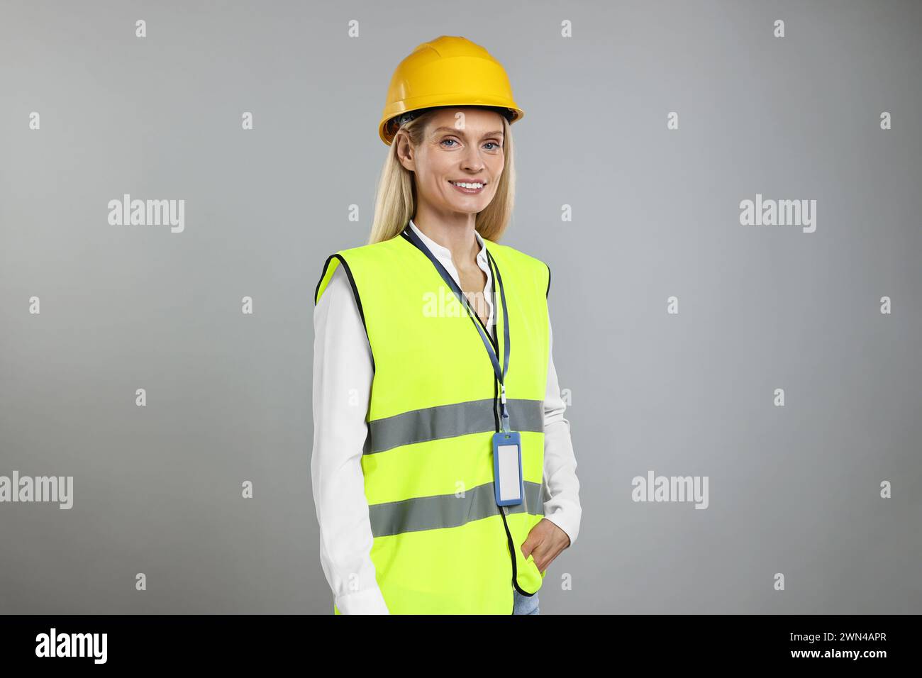 Engineer with hard hat and badge on grey background Stock Photo - Alamy