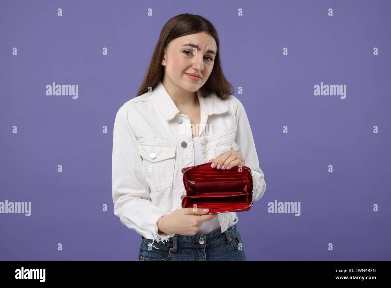 Sad woman showing empty wallet on purple background Stock Photo - Alamy