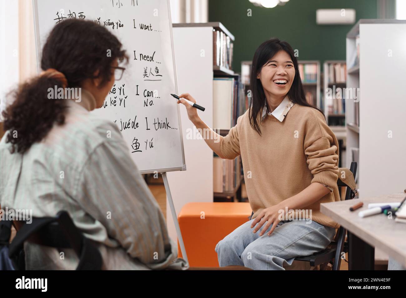 Portrait of young Asian woman laughing cheerfully pointing at ...