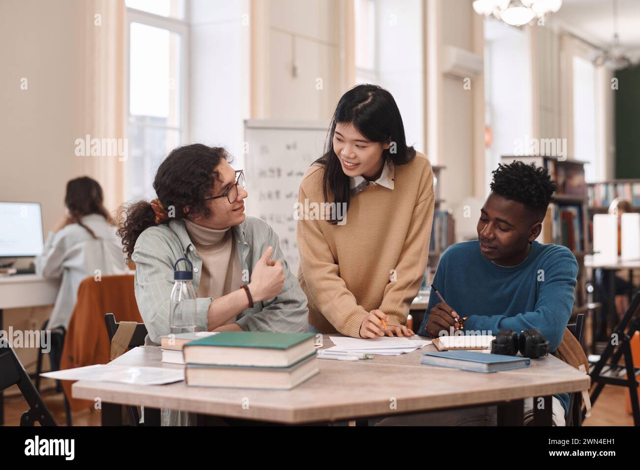 Front view at multiethnic group of three students studying together ...